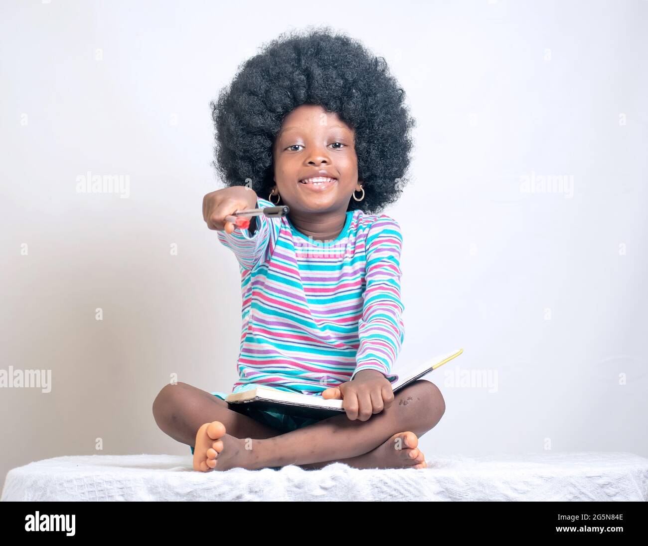 African girl child with an afro hair style shows her love for education ...