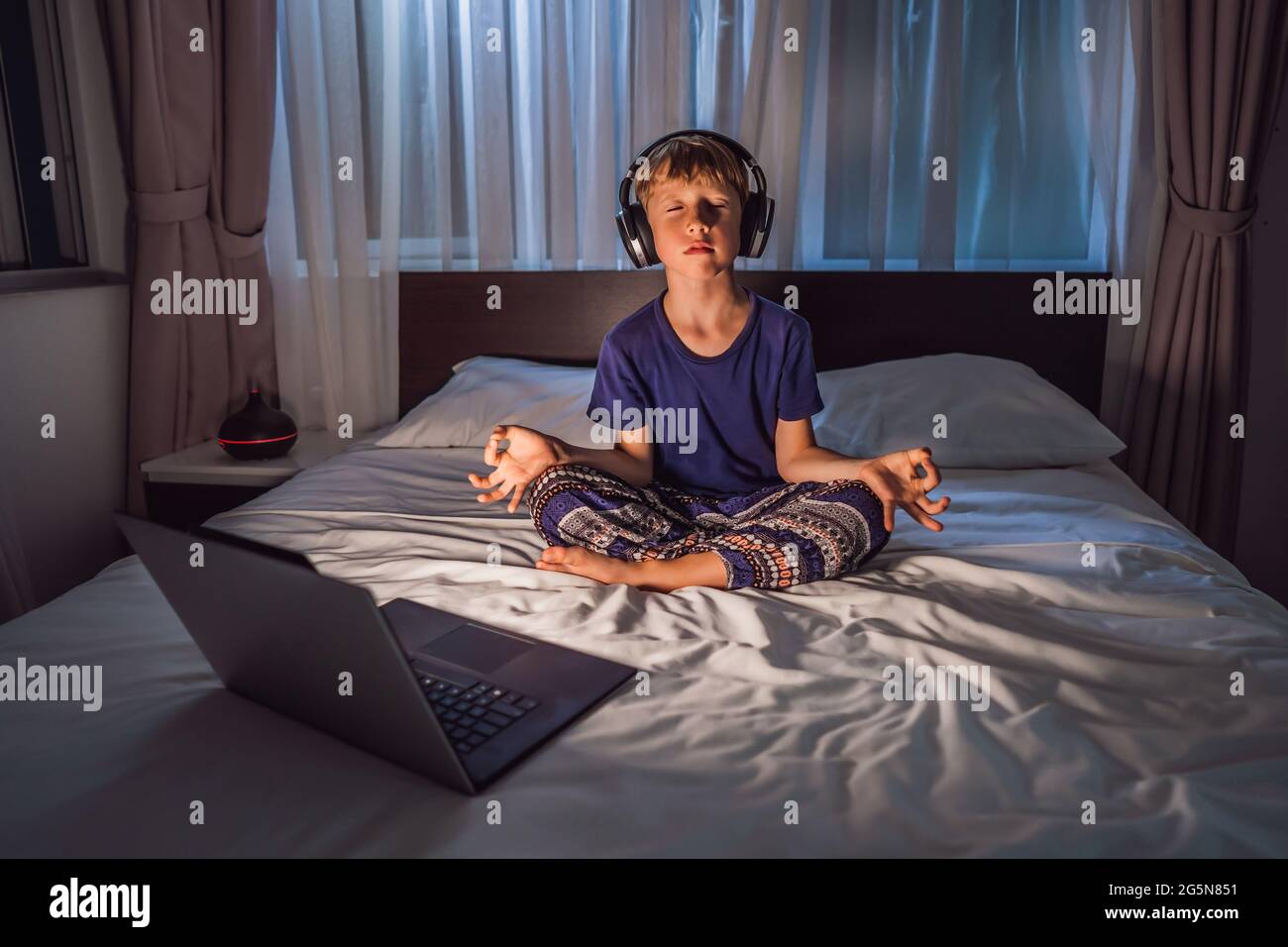 Boy meditates on bed using meditation app. sport, technology and ...