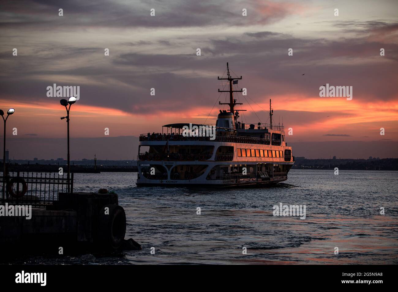 At the Kadikoy dock, sunset is seen reflected on the windows of the ...