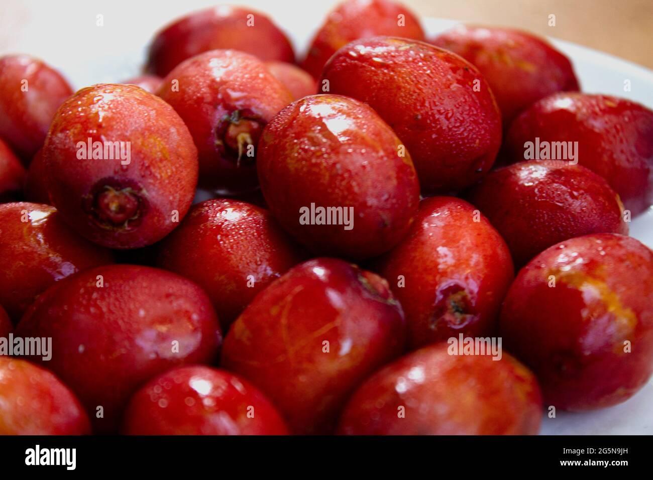 Red dates isolated on a ceramic plate Stock Photo - Alamy