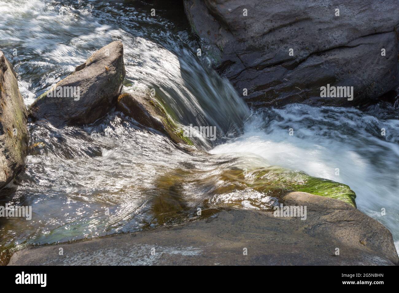 Mountain water flows between stones Stock Photo - Alamy