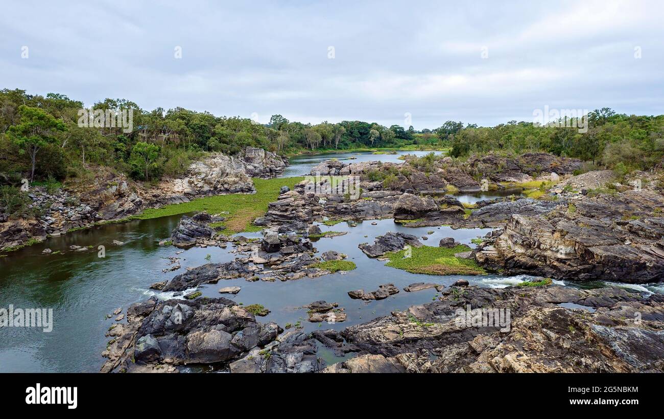 Aerial over rocks and weed landscape downstream from a weir regulating ...