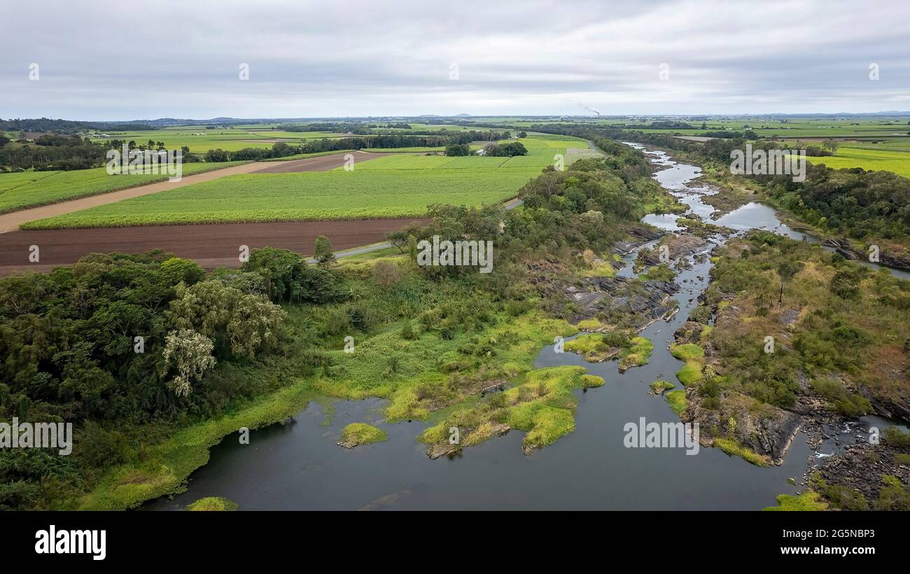 Aerial over rocks and weed landscape downstream from a weir regulating ...