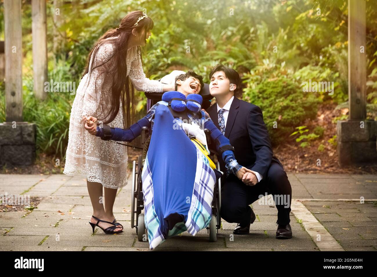 Bride and groom with disabled child in wheelchair outdoors Stock Photo ...