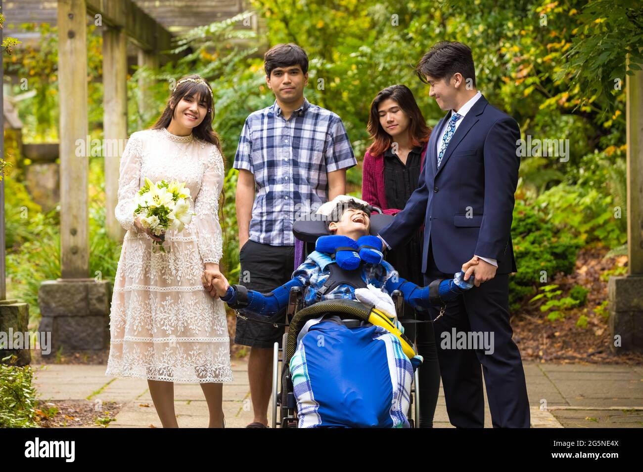 Newly married bride and groom posing together with family outdoors ...