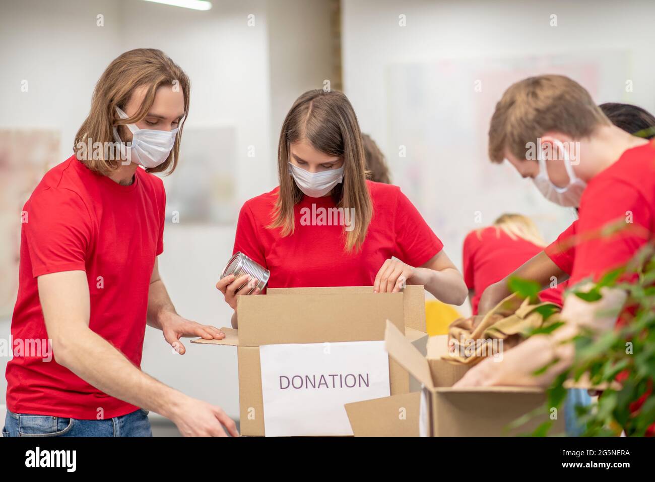Volunteers wearing protective masks packing donation boxes Stock Photo ...