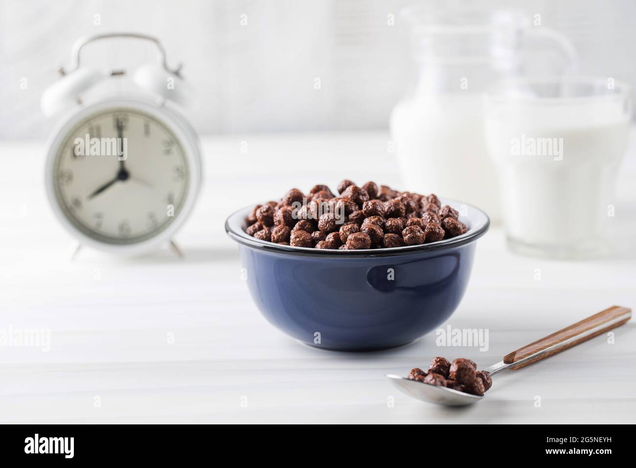 Round cocoa flakes in a plate, with a mug of milk and an alarm clock in ...
