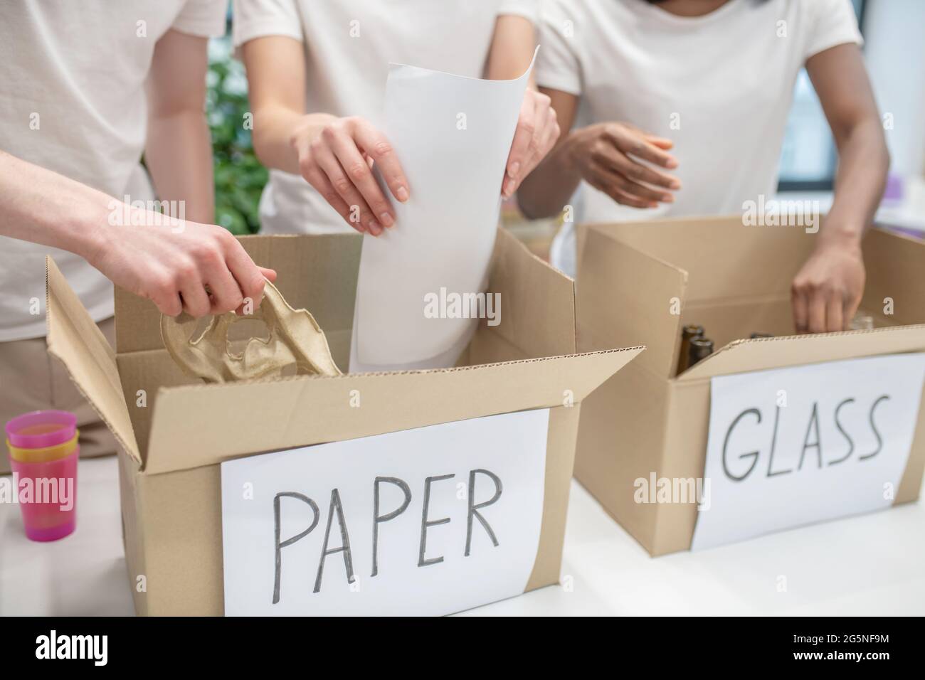 Hands of young people sorting paper and glass Stock Photo - Alamy