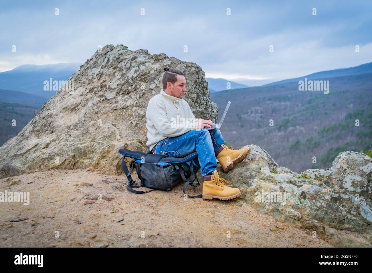 Blogger man sitting on a rock ad using a laptop Stock Photo - Alamy