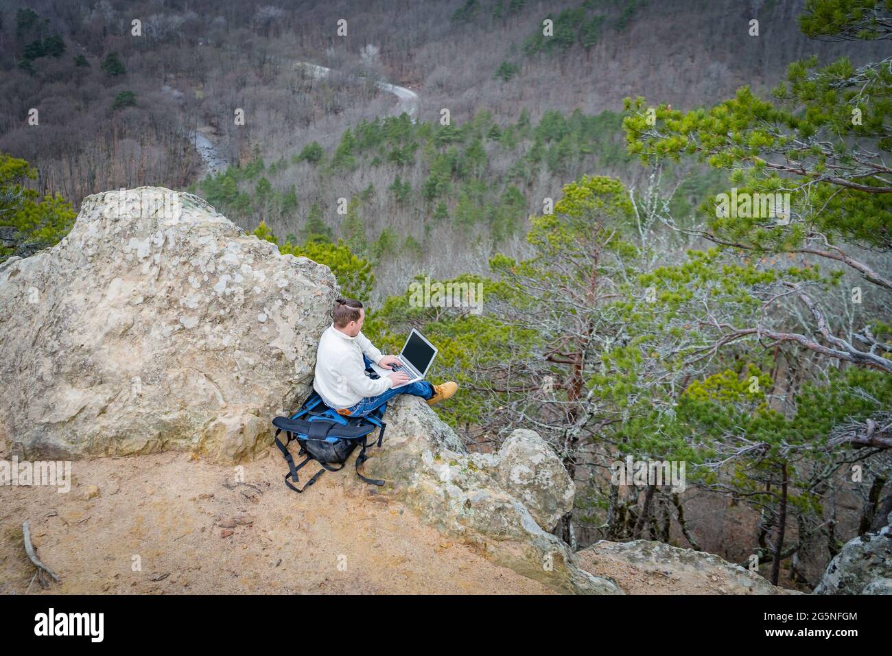 Blogger man sitting on a rock ad using a laptop Stock Photo - Alamy