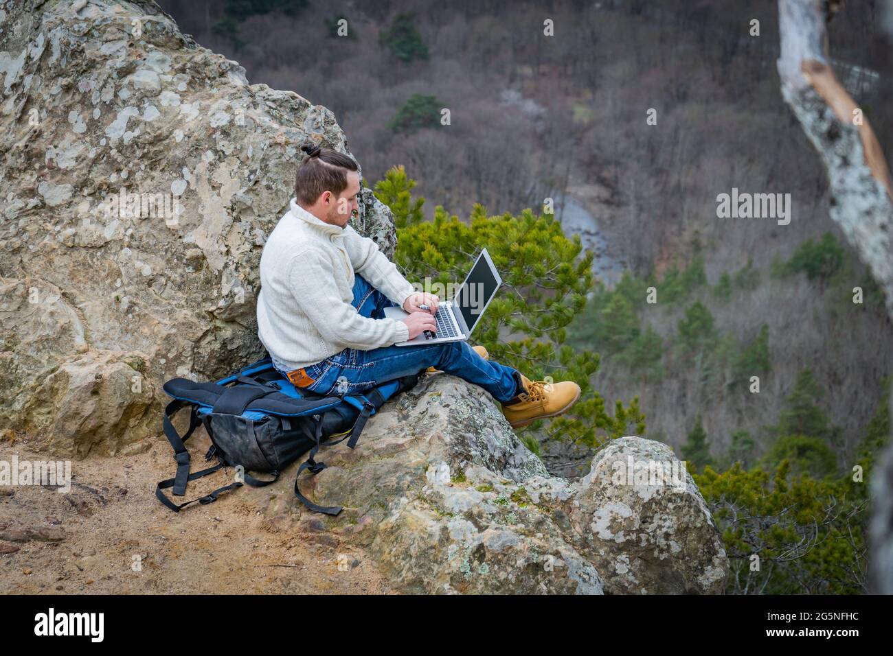 Blogger man sitting on a rock ad using a laptop Stock Photo - Alamy