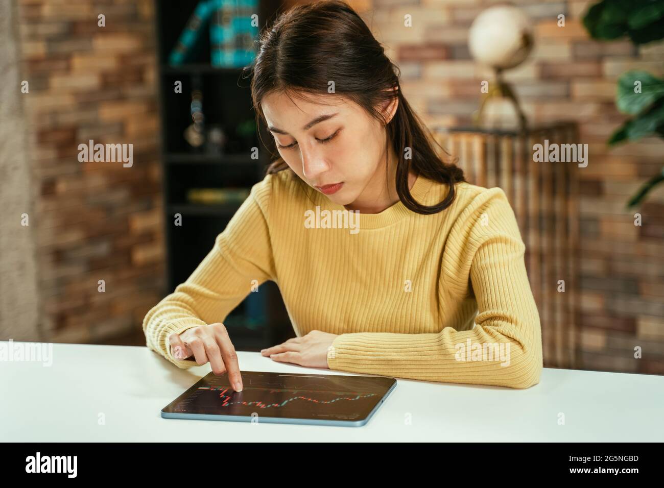 Successful young Asian female broker working and reading stock market ...