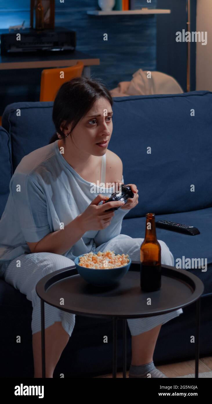 Gamer using joystick playing video games with joystick sitting on couch ...