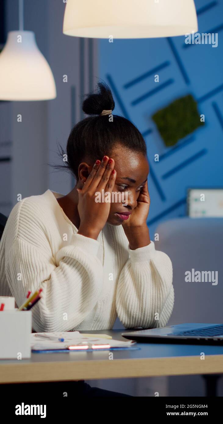 Overworked african manager woman massaging head while sitting at ...