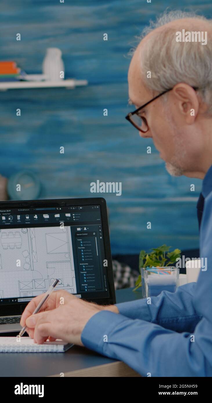 Senior man architect analysing digital prototype with plans from laptop ...