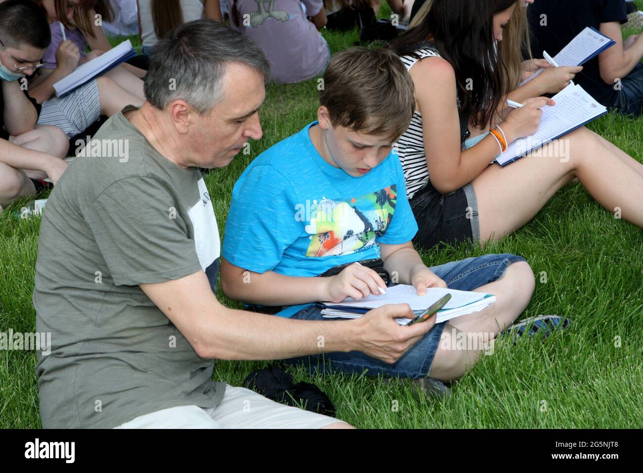 DNIPRO, UKRAINE - JUNE 28, 2021 - A man helps a boy take dictation in ...