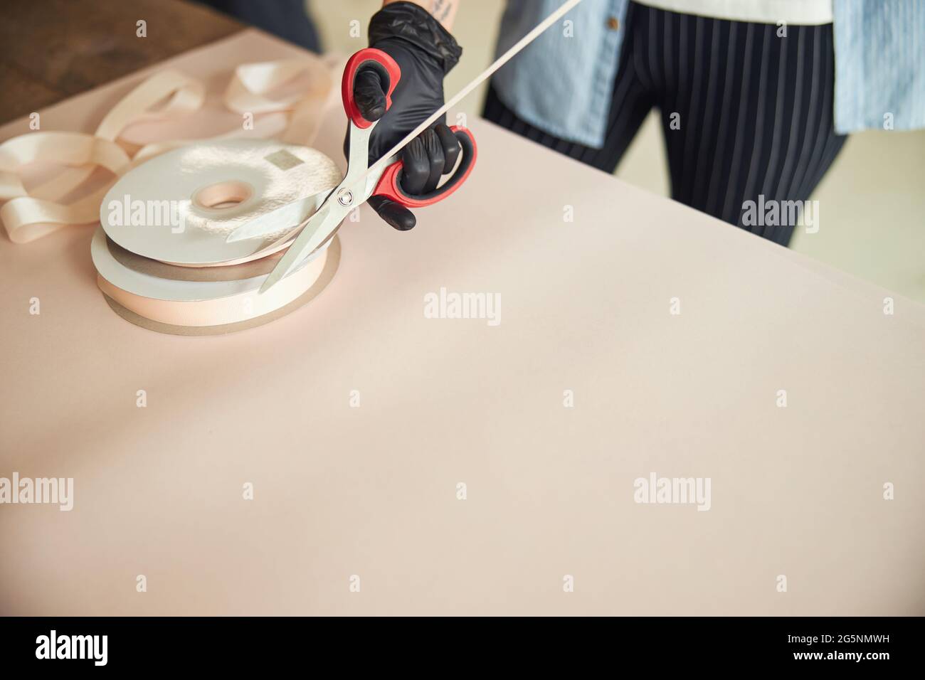 Gloved hand snipping off a piece of satin ribbon Stock Photo - Alamy