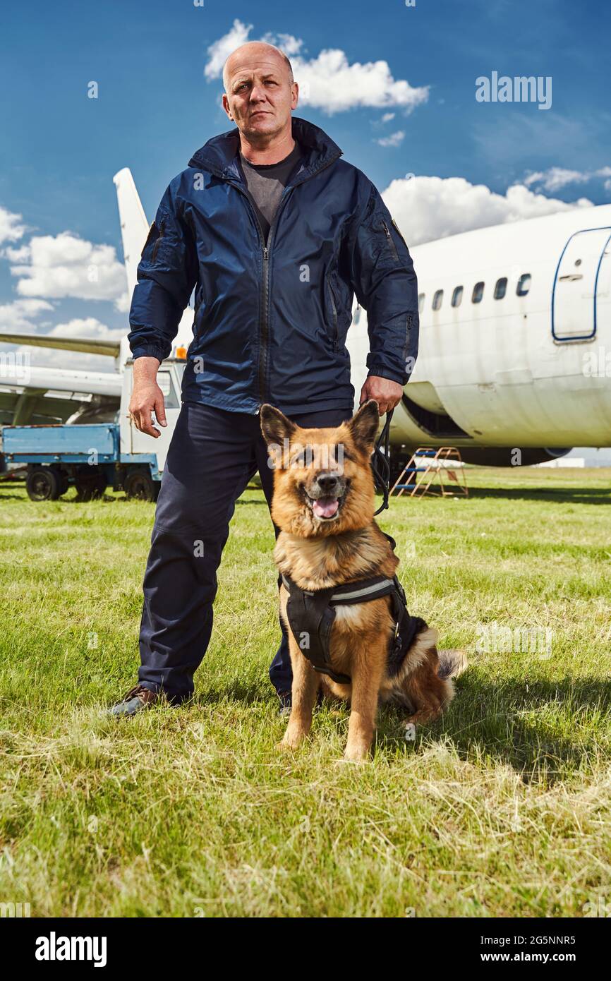 Security officer with detection dog standing outdoors at airfield Stock ...