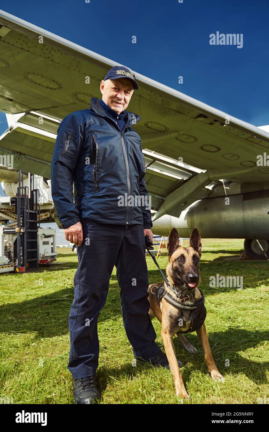 Security officer with dog standing near plane at aerodrome Stock Photo ...