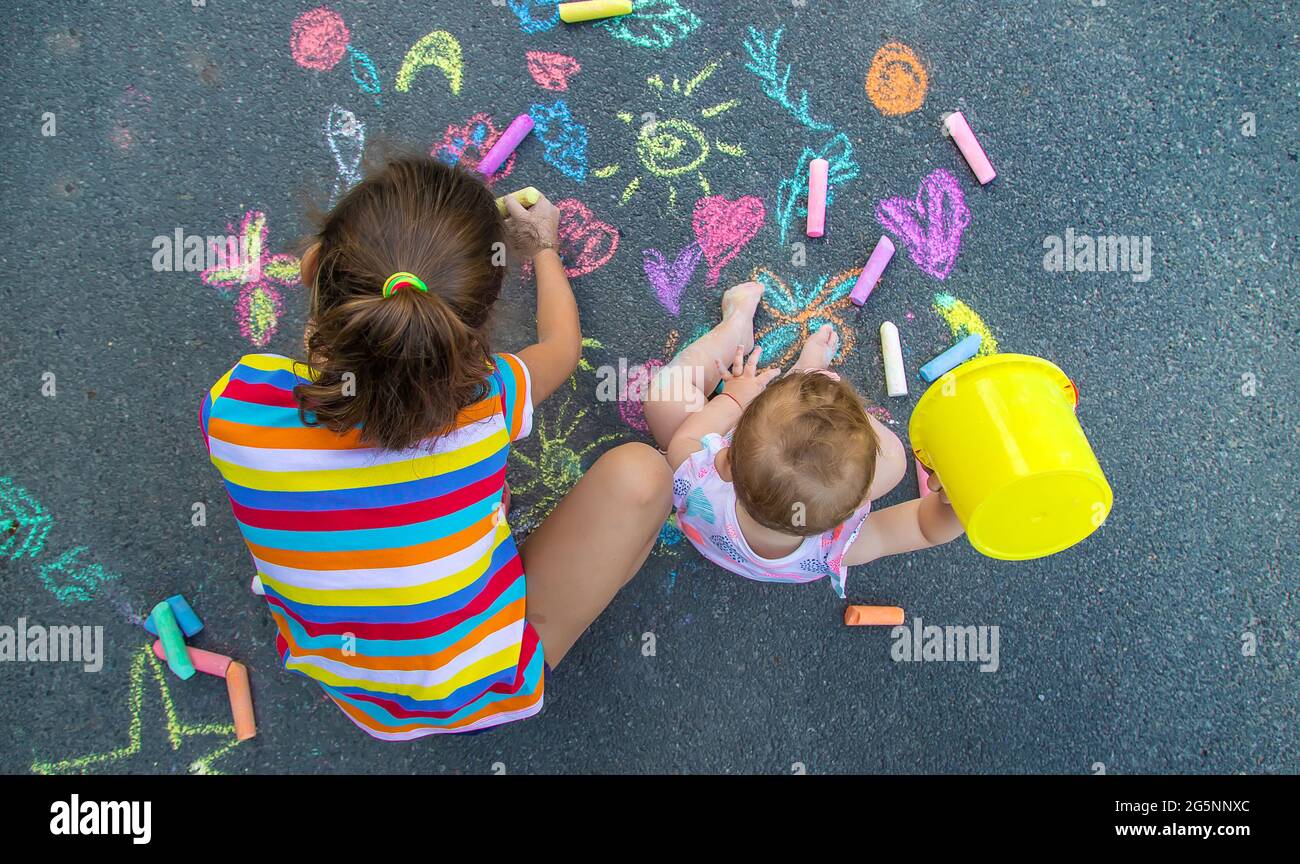The child draws with chalk on the asphalt. Selective focus. Kids Stock ...