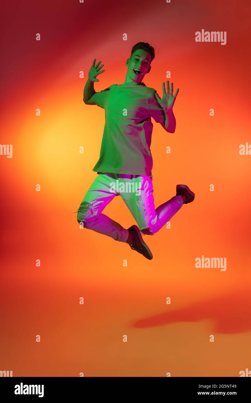 Portrait of Caucasian young man jumping, dancing isolated on orange ...