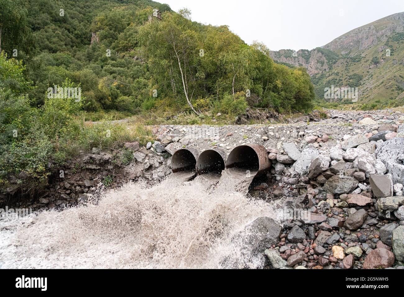 Mountain river flows through pipes Stock Photo - Alamy