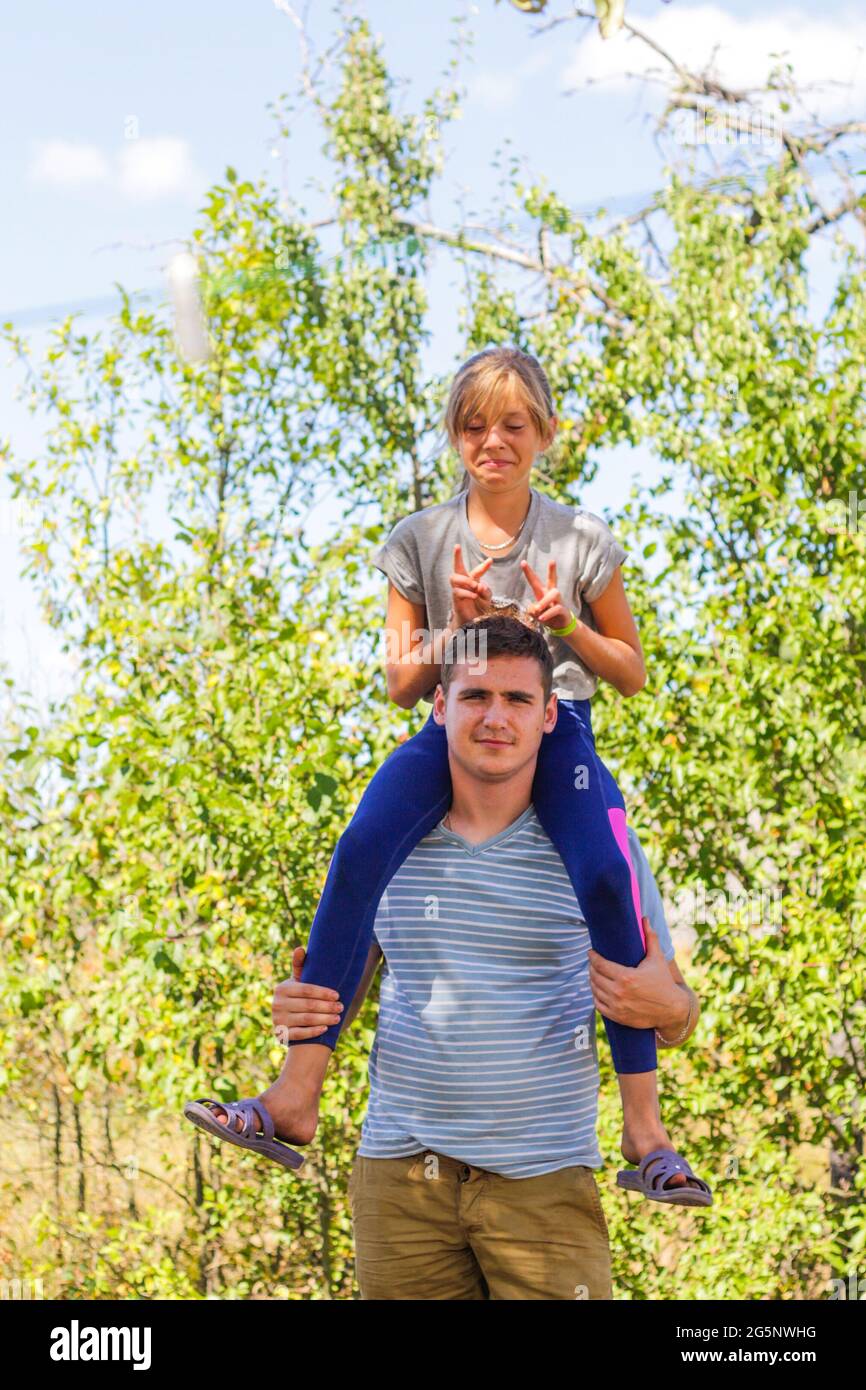 Defocused brother giving sister ride on back. Portrait of happy girl on ...