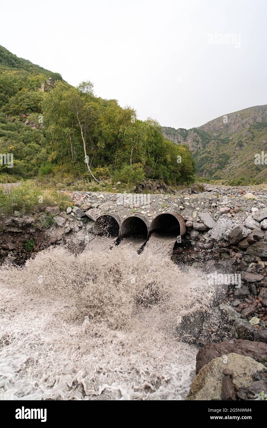 Mountain river flows through pipes Stock Photo - Alamy