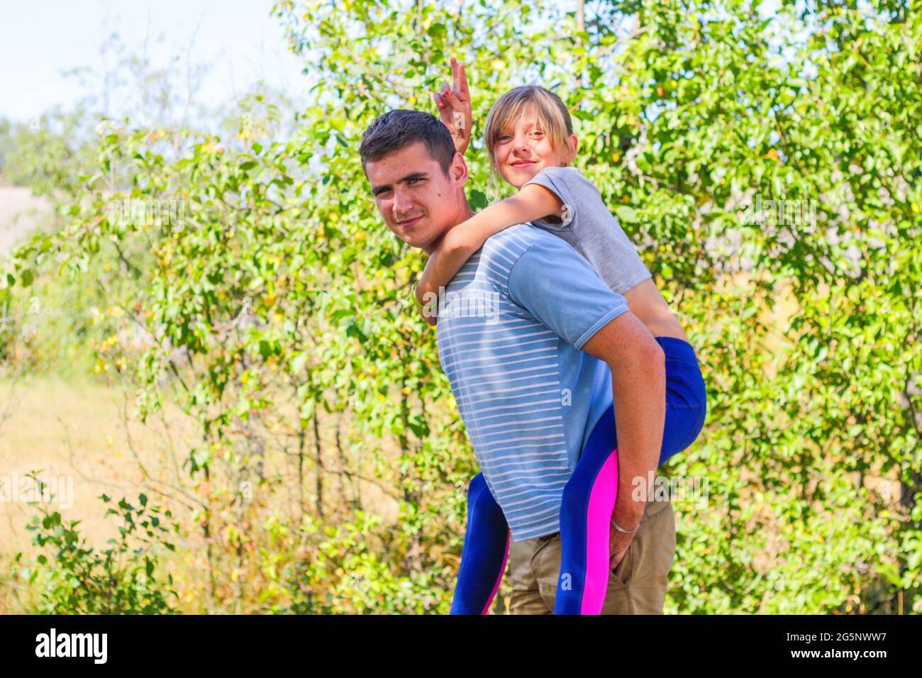Defocused brother giving sister ride on back. Portrait of happy girl ...