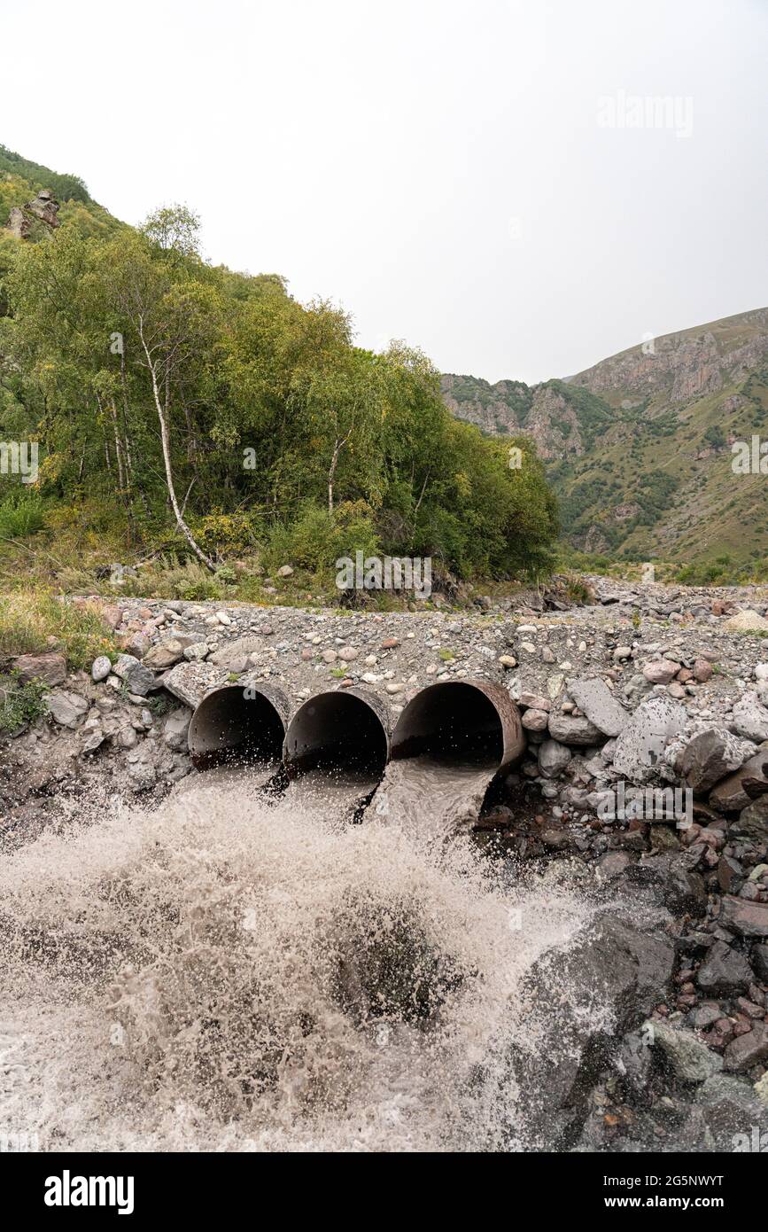 Mountain river flows through pipes Stock Photo - Alamy