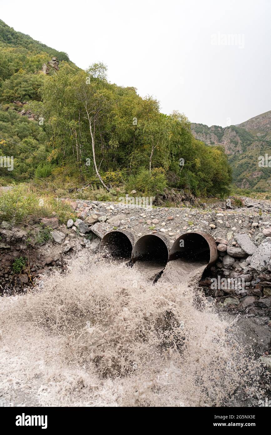 Mountain river flows through pipes Stock Photo - Alamy