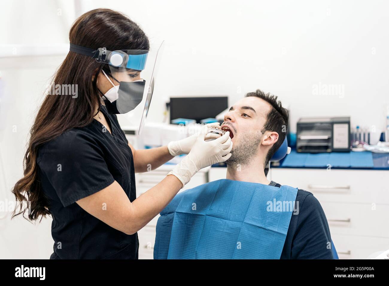 Female dentist wearing face shield isolation mask working with male ...