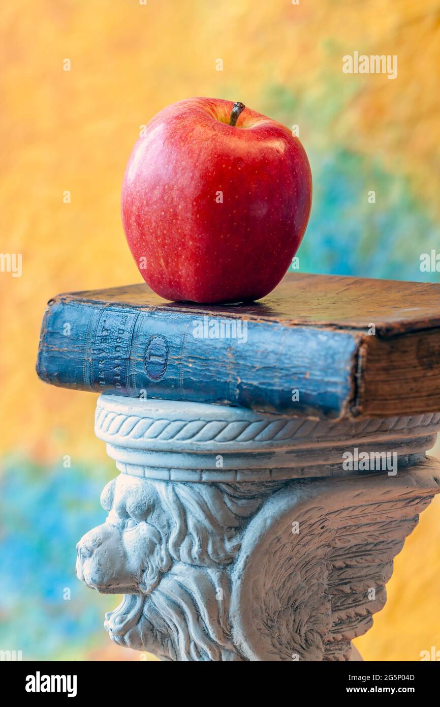 Red apple and very old book on statue Stock Photo - Alamy