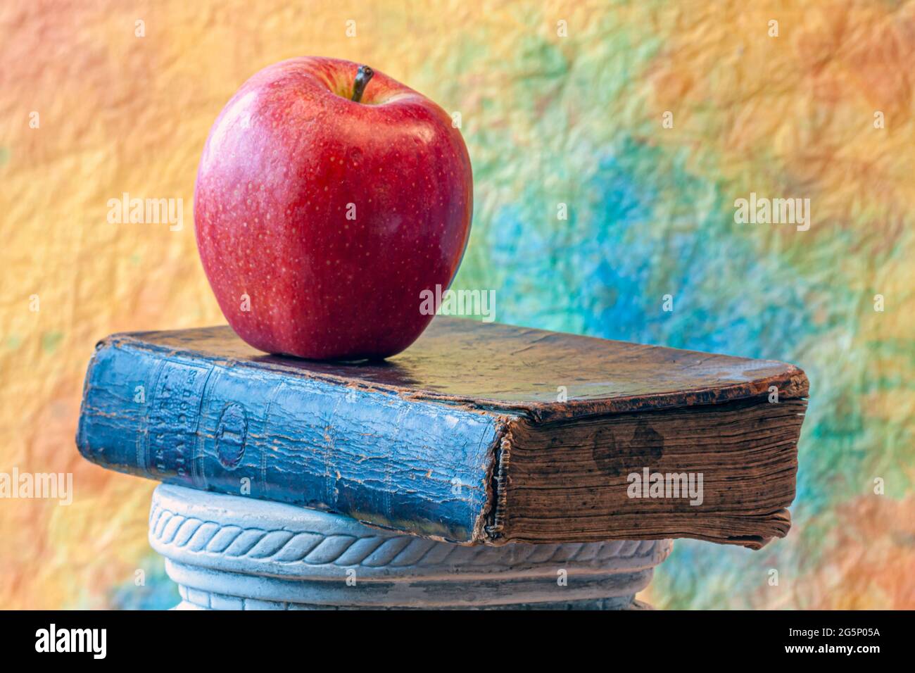 Red apple and very old book on statue Stock Photo - Alamy