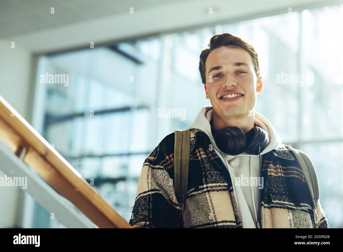 Confident male student standing in high school. Young man at university ...