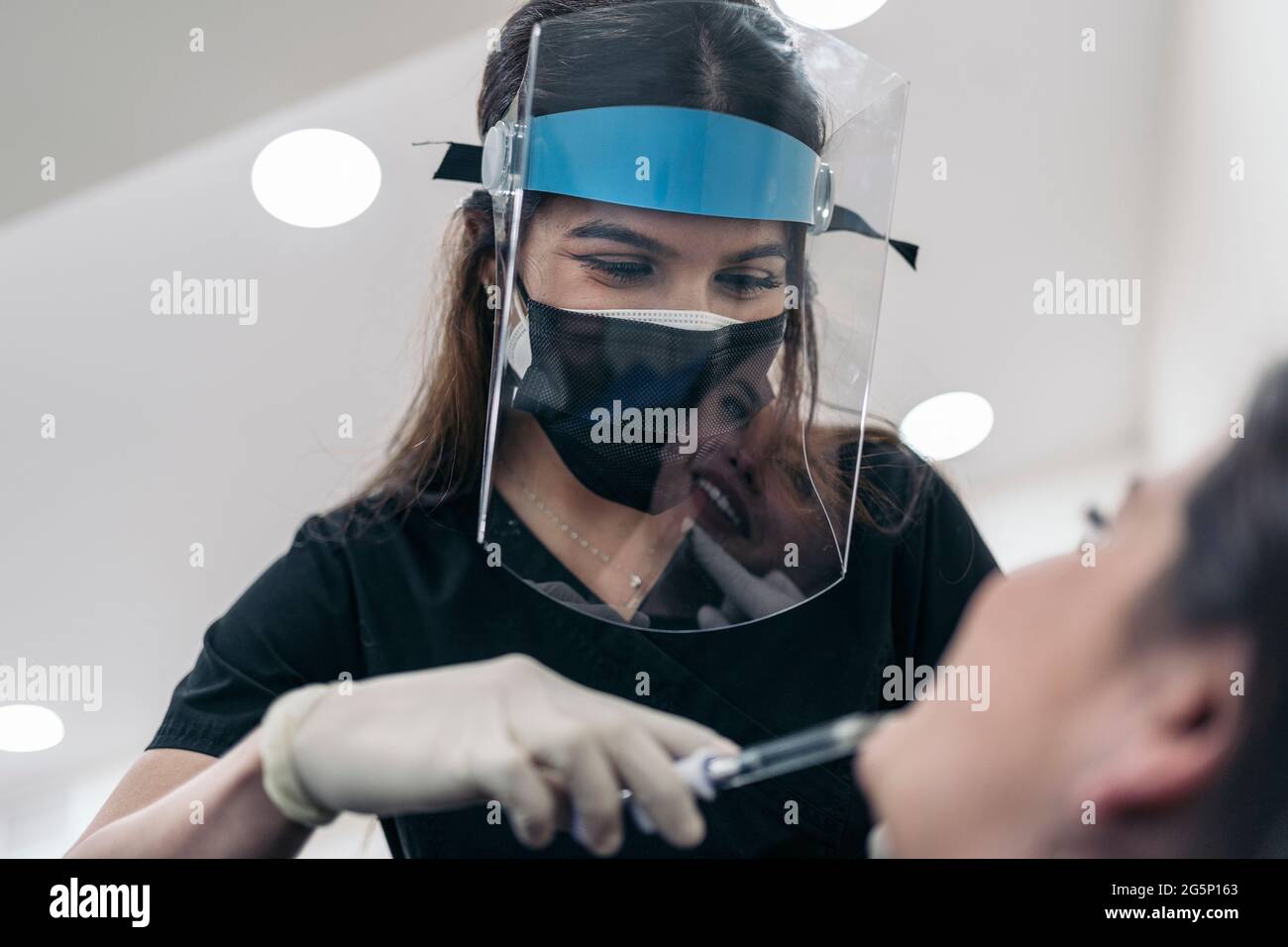 Professional medic worker wearing isolation mask putting botox ...