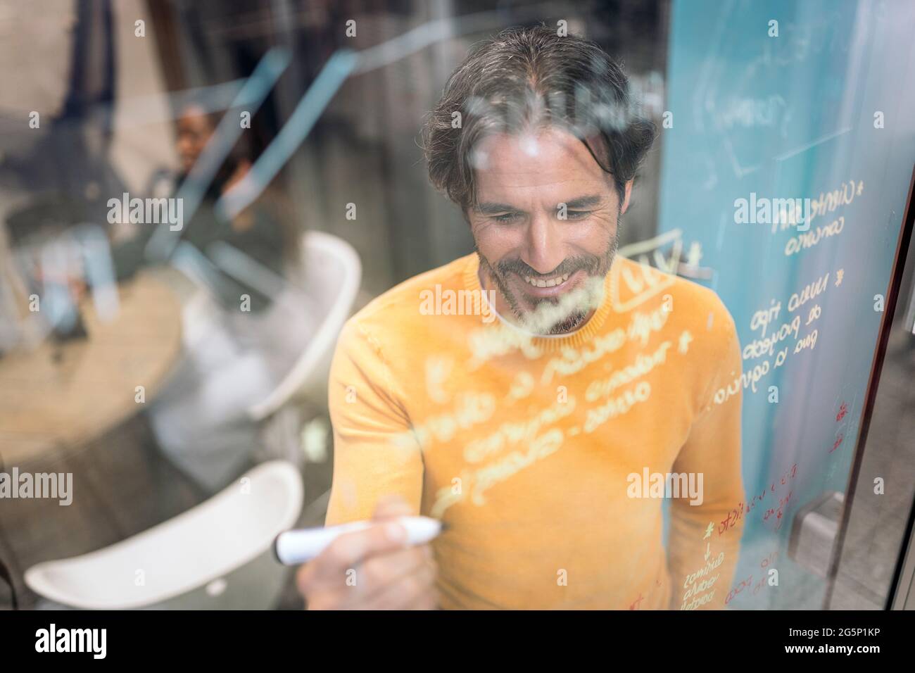 Bearded male office worker writing in white board and smiling. Co ...
