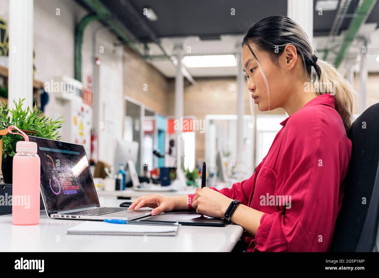 Focused asian office worker sitting in her desk and working with her ...