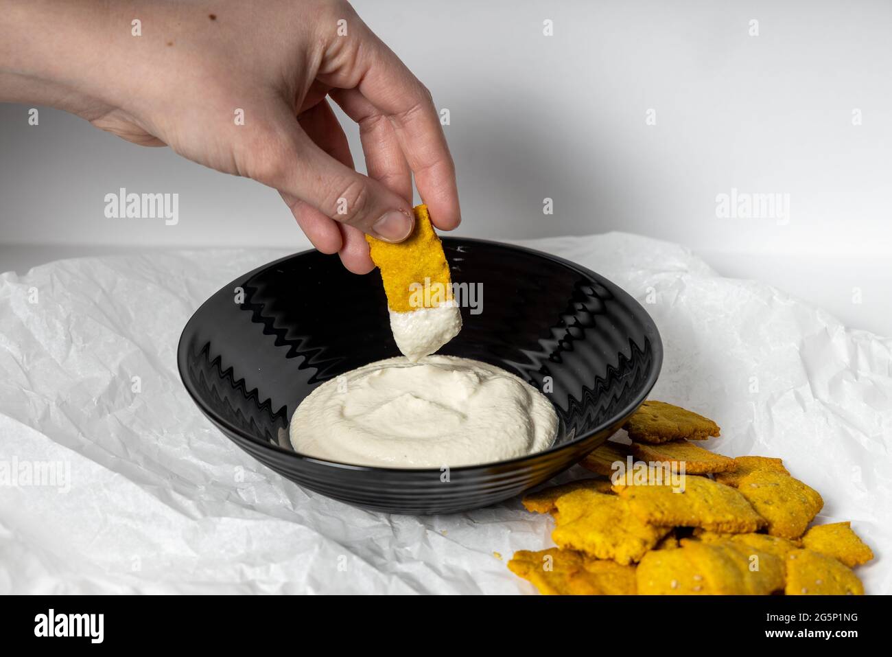 Hand dipping a chickpea flour snack into vegan mayonnaise Stock Photo ...