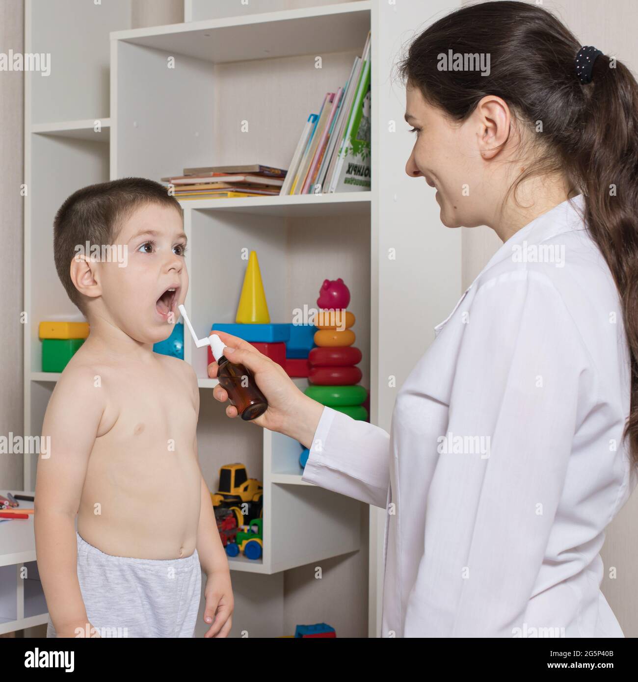 A pediatrician or nurse and a boy 3-4 years old. Throat spray ...