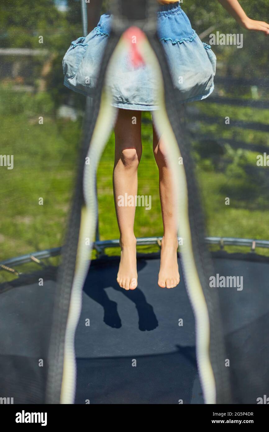 Leg of little child jumping on trampoline in the backyard of the house ...