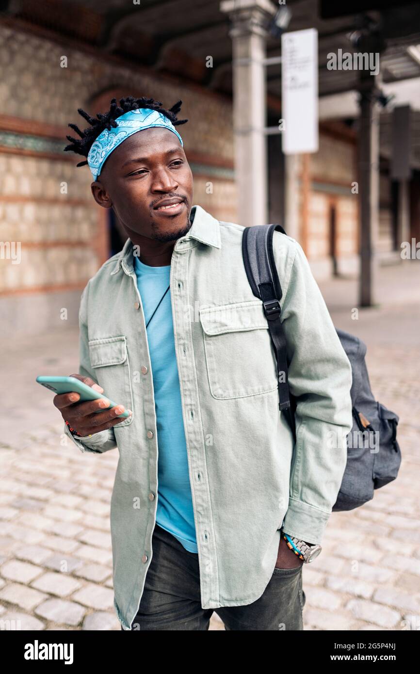 Handsome and cool african man walking in the street and using his ...