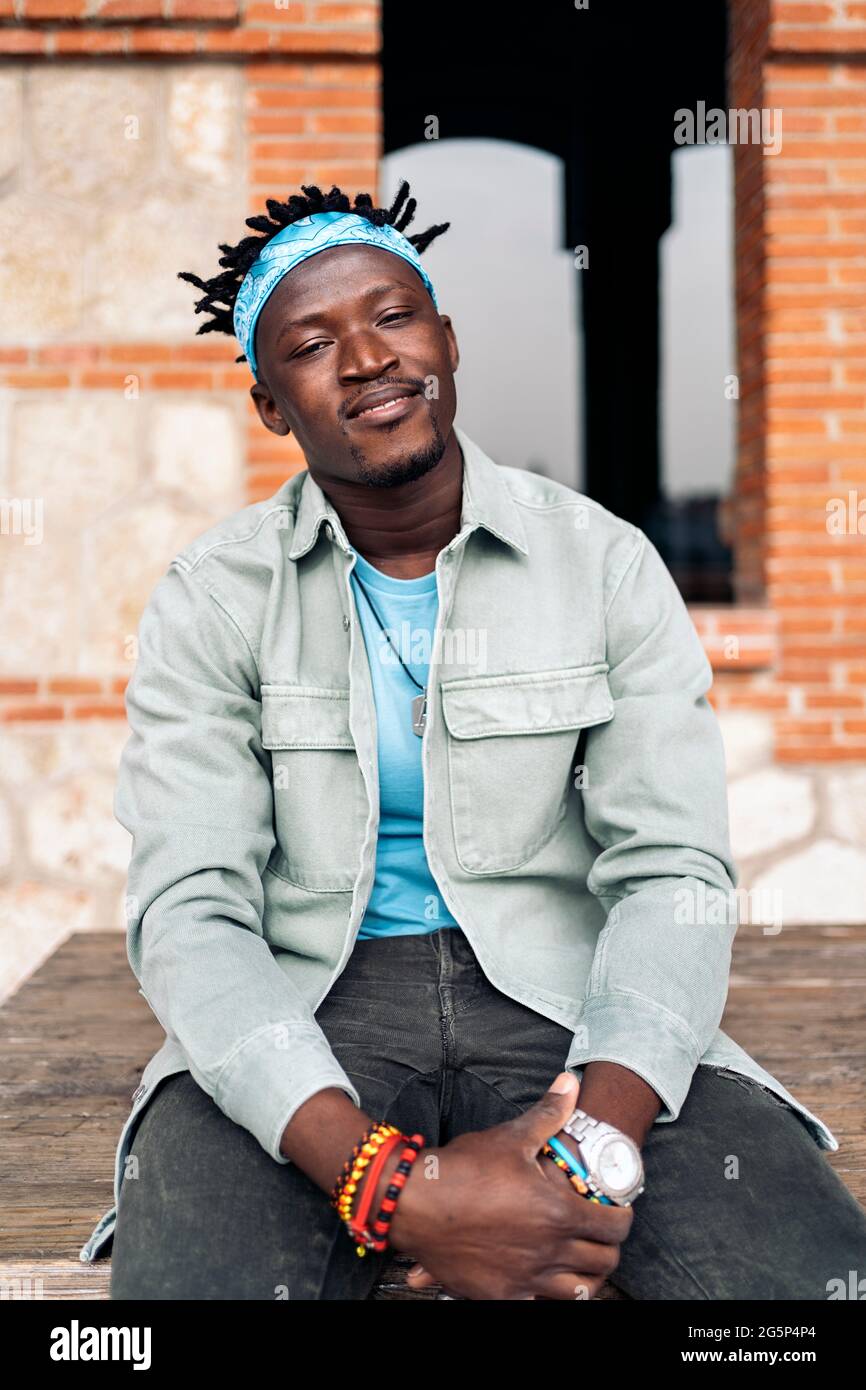 Young and stylish african man sitting in a table and looking at camera ...
