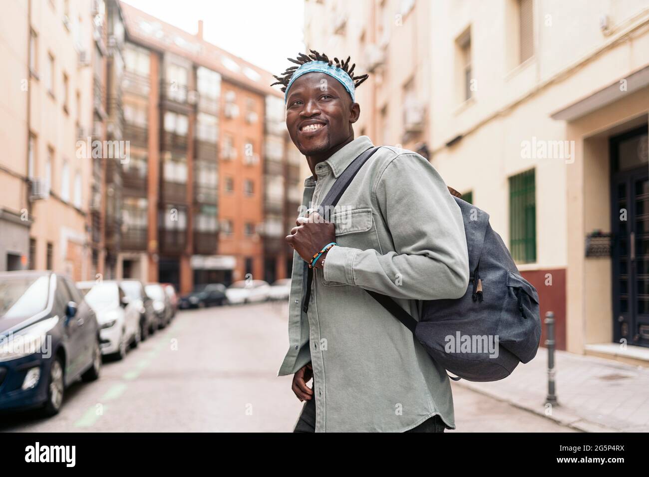 Attractive african boy with dreadlocks and wearing backpack walking in ...