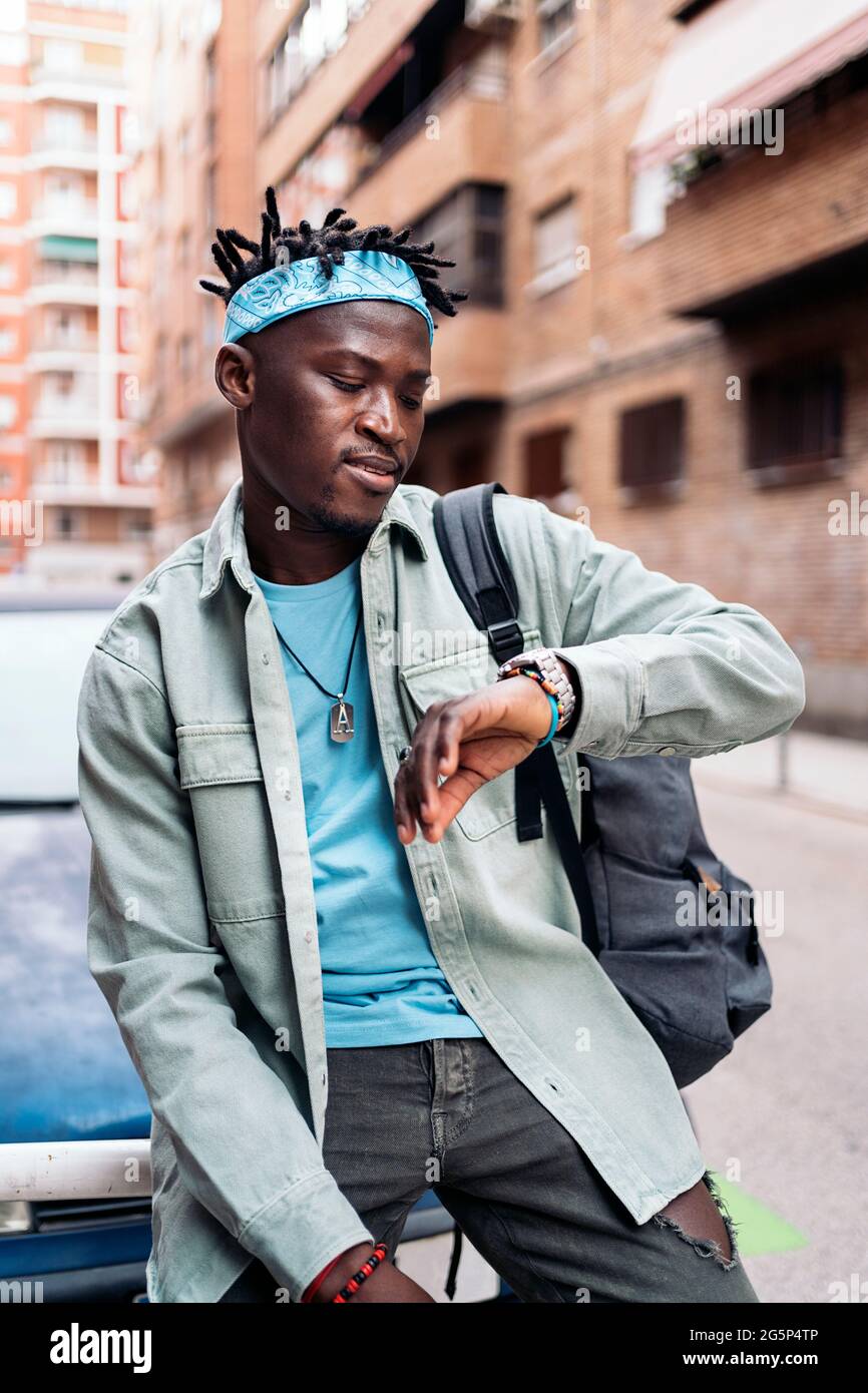Attractive african boy with dreadlocks standing in the street and using ...