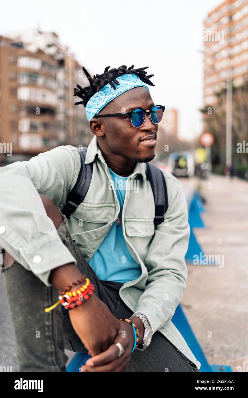 Young and confident african man sitting in the street and looking to ...