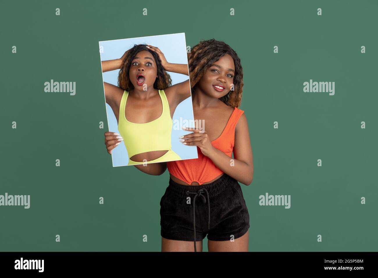Young attractive girl holding her portrait, photo isolated on green ...