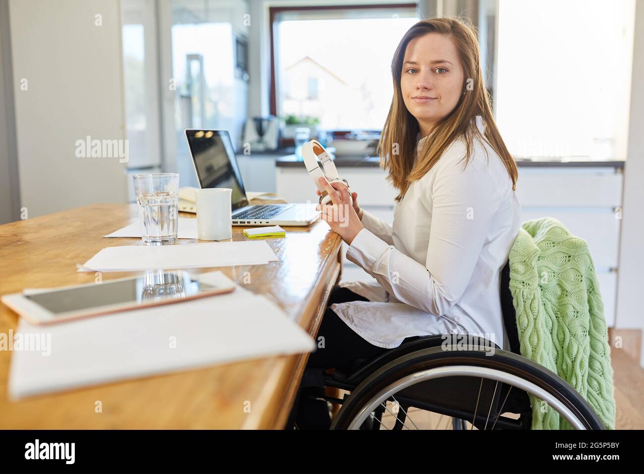 Disabled business woman in wheelchair working on laptop computer online ...
