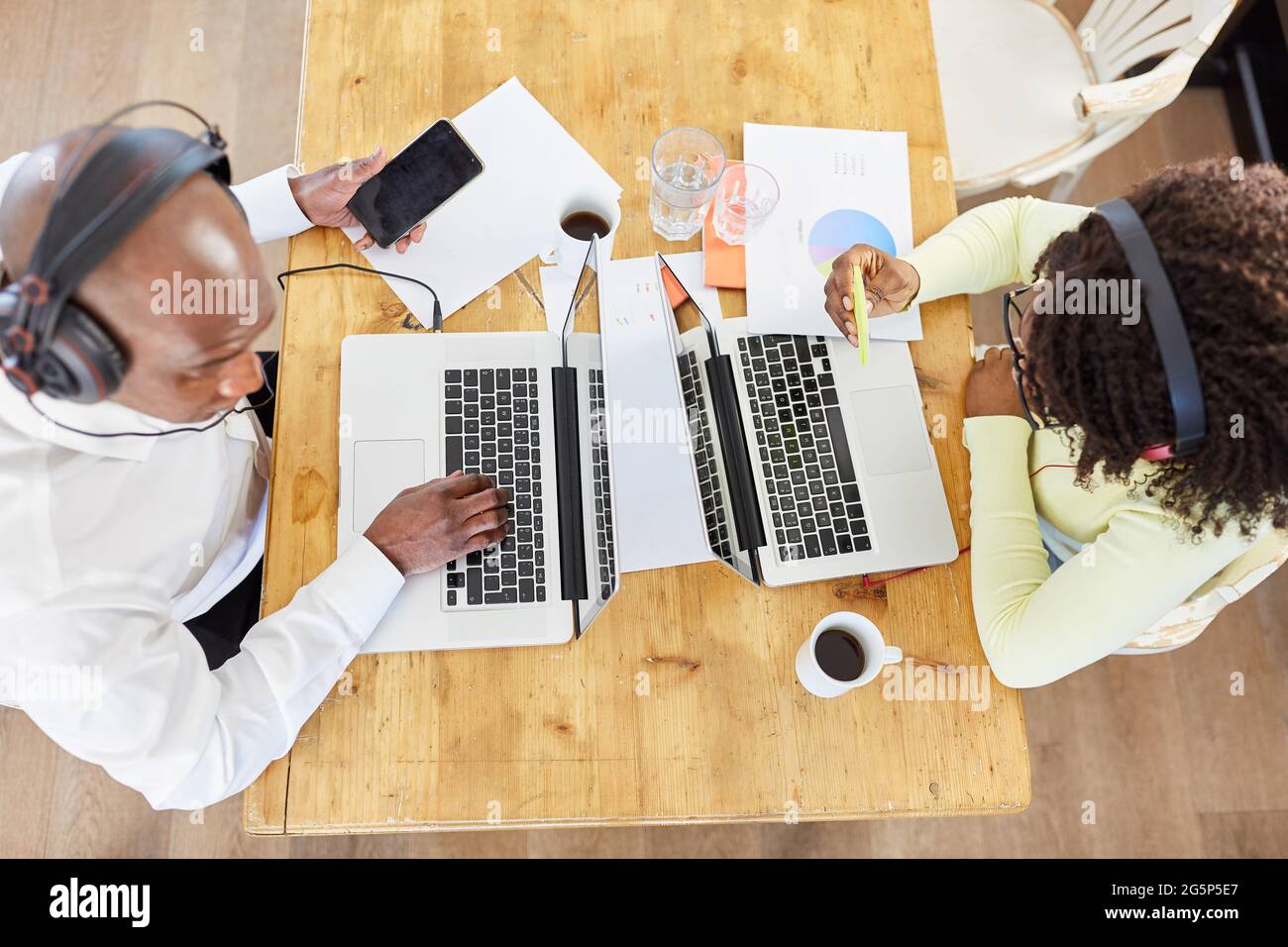 Two business people working on laptop computer in home office at table ...