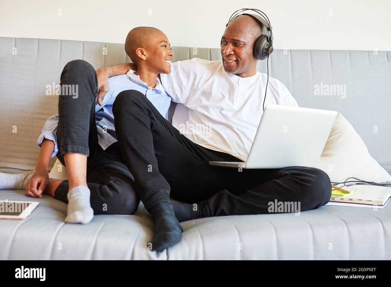 Father using laptop computer on the sofa during childcare with his son ...